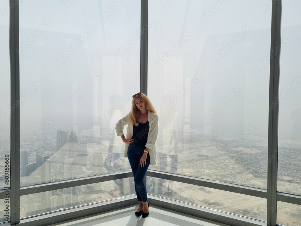Beautiful girl stands by the window of skyscraper with an amazing ...