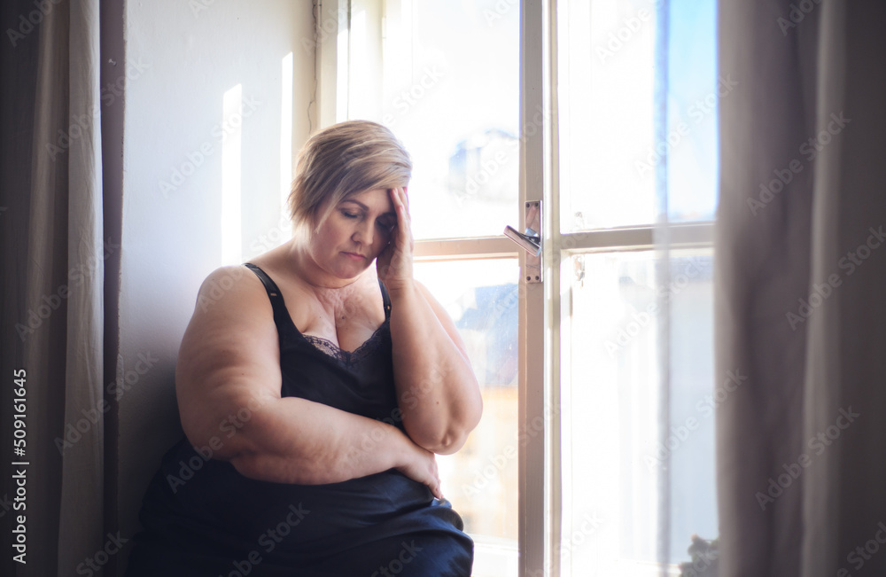 Depressed lonely fat woman in underwear sitting near window,looking ...