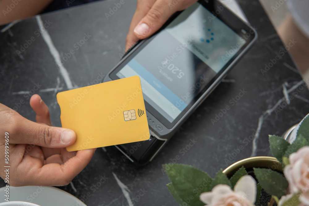 Hand holding yellow credit card to make digital payment by dataphone ...