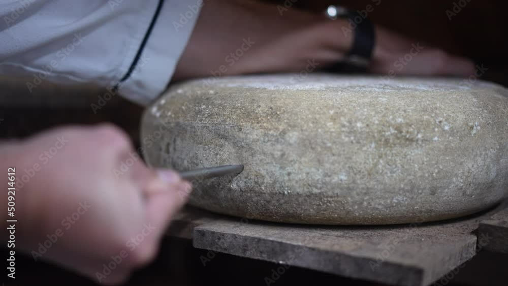 Male Caucasian hand inserting cheese trier in cheese wheel turning tool ...