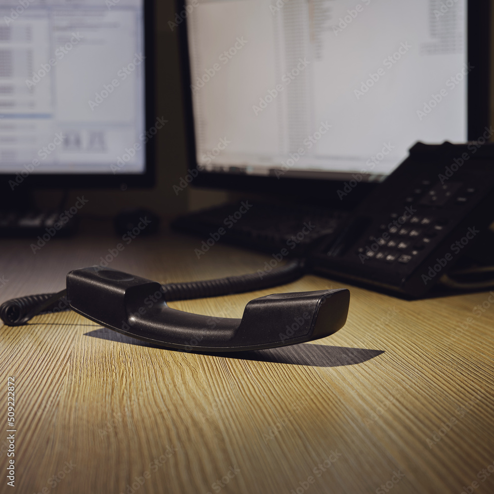 Handset of the landline phone lies on the office desk with computer ...