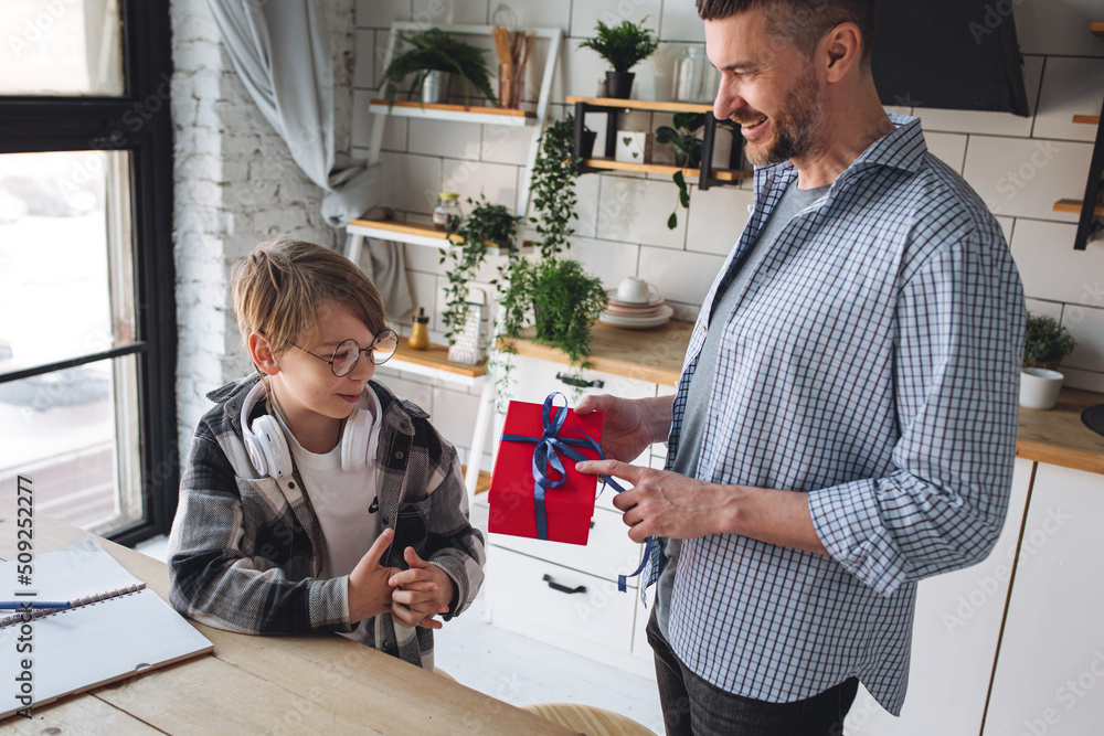 Handsome young father giving a birthday present in a red box to his ...