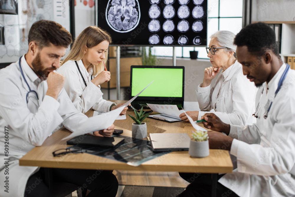 Group of four pensive medical worker looking at patient presription and ...