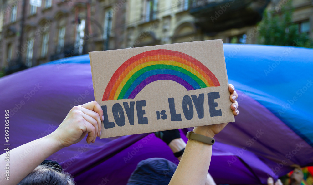 Woman holding placard sign Love is Love with rainbow, symbol of LGBT ...