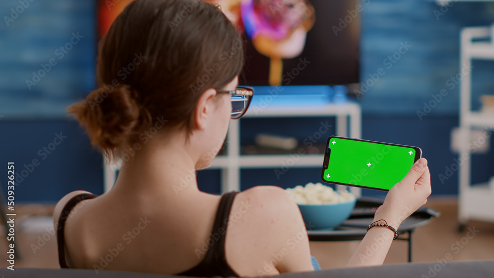 Young woman holding horizontal smartphone with green screen using ...