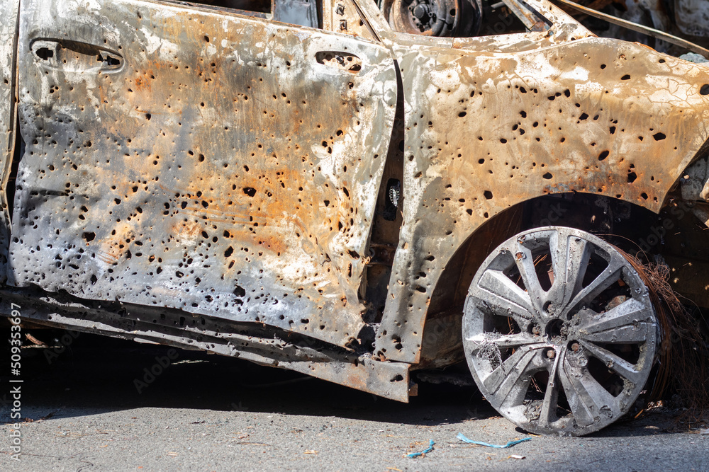 Burnt car body riddled with bullets. Russia's war against Ukraine. Shot ...
