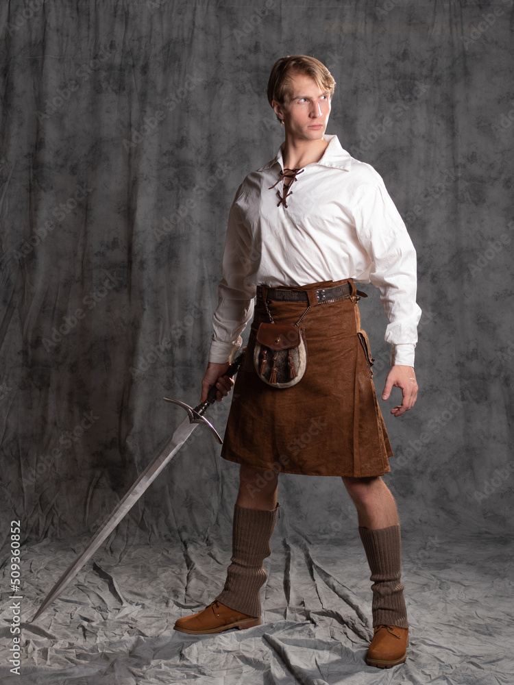 A young man in a leather kilt and a white lace-up blouse. A Scottish ...