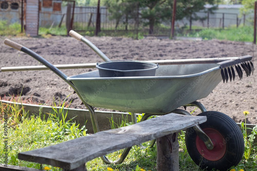 Gray metal garden wheelbarrow with two handles and one wheel. The ...