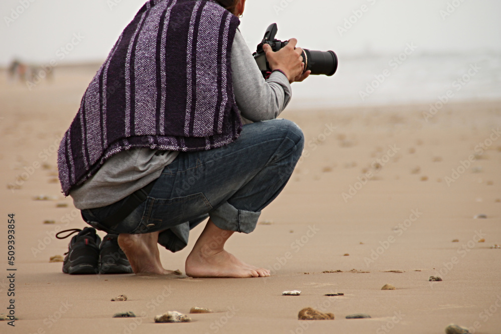 Persona agachada haciendo fotos en la playa con una cámara reflex Stock ...