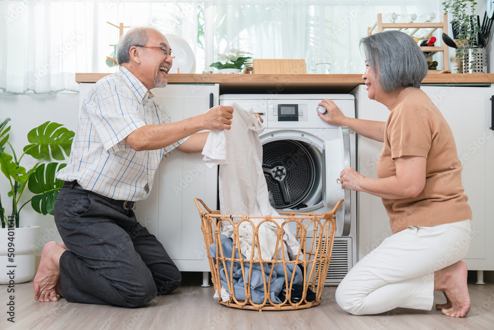Happy Asian senior older man helping his wife put clothes in washing ...