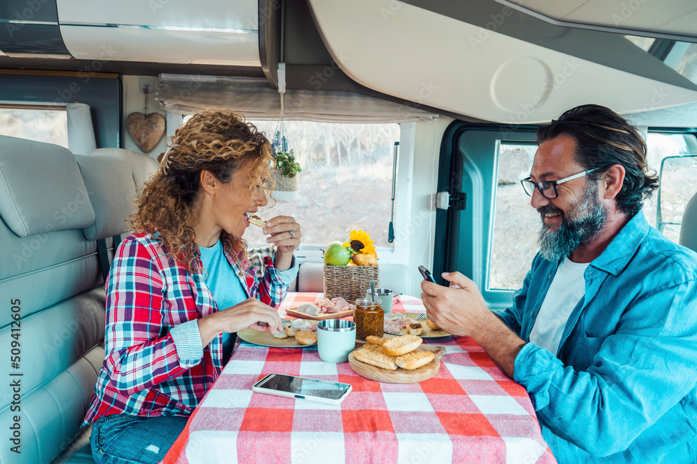 Man and woman have lunch together inside a modern camper van rv vehicle ...