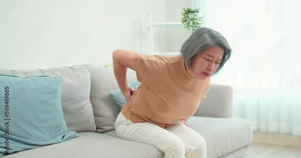 Elderly woman Asian has sudden back pain as he gets up from the sofa in ...