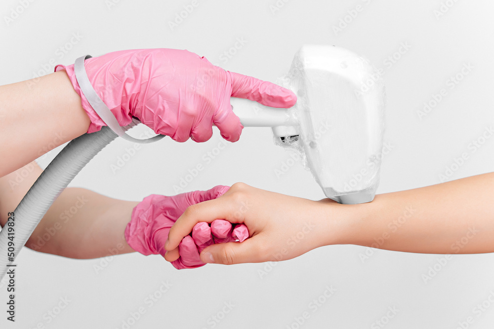 Laser hair removal on the hand on a white background. Pink gloves hold ...