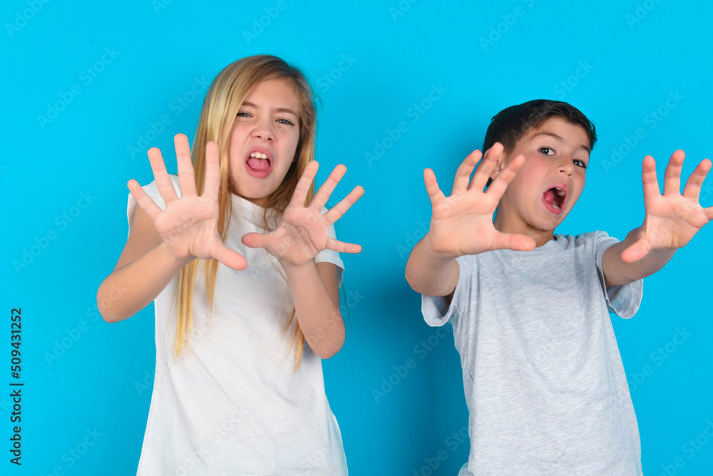 Dissatisfied two kids boy and girl standing over blue studio background ... Dissatisfied two kids boy and girl standing over blue studio background ...
