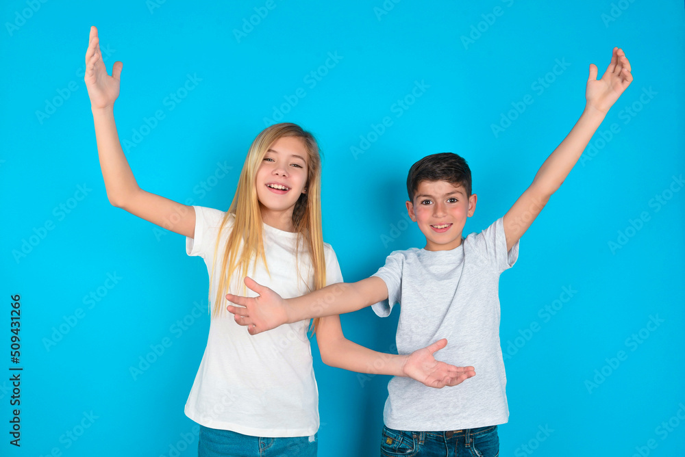 Cheerful two kids boy and girl standing over blue studio background ...