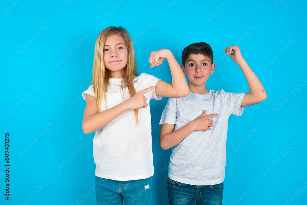 Smiling two kids boy and girl standing over blue studio background ...