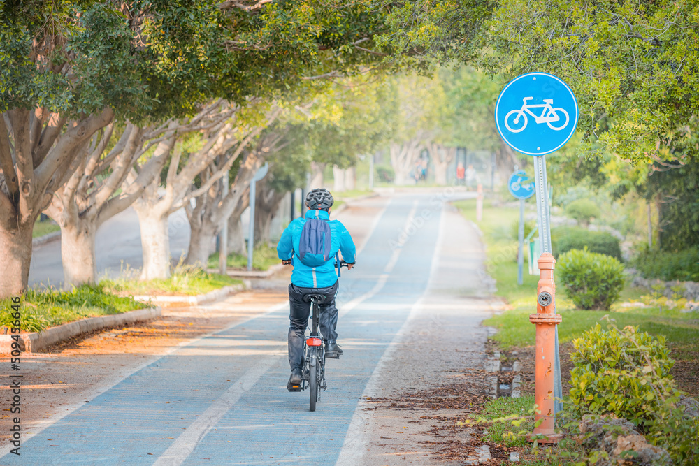 Cyclist ride along a bike path in a park with painted pavement and road ...