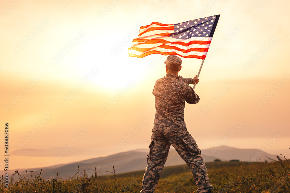 Male soldier in the uniform of the American army waving the US flag on ...