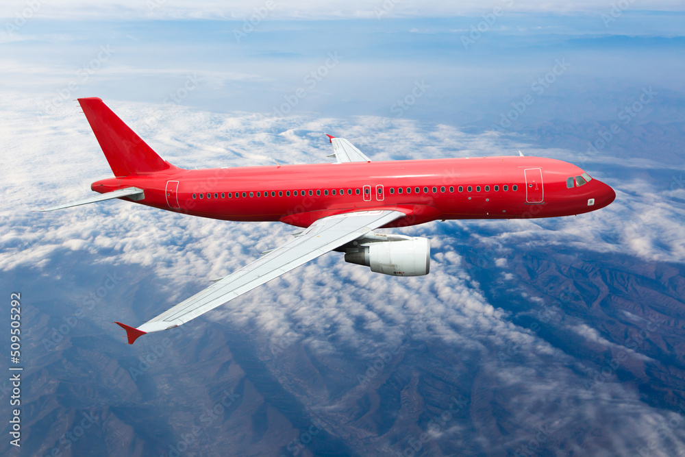 Red passenger plane in flight. Aircraft flies in the sky above the ...