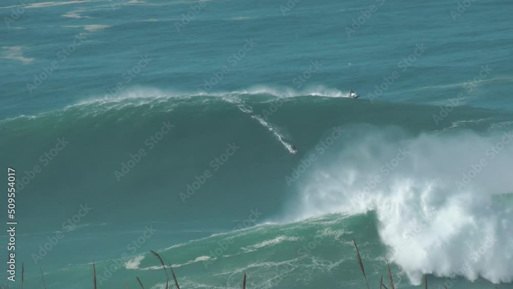 Surfer riding giant wave near historical landmark Fort of Sao Miguel ...