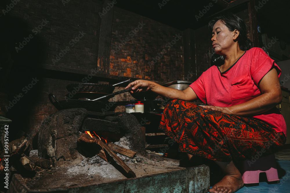 Asian local woman is cooking in traditional stove at wood cubicle ...