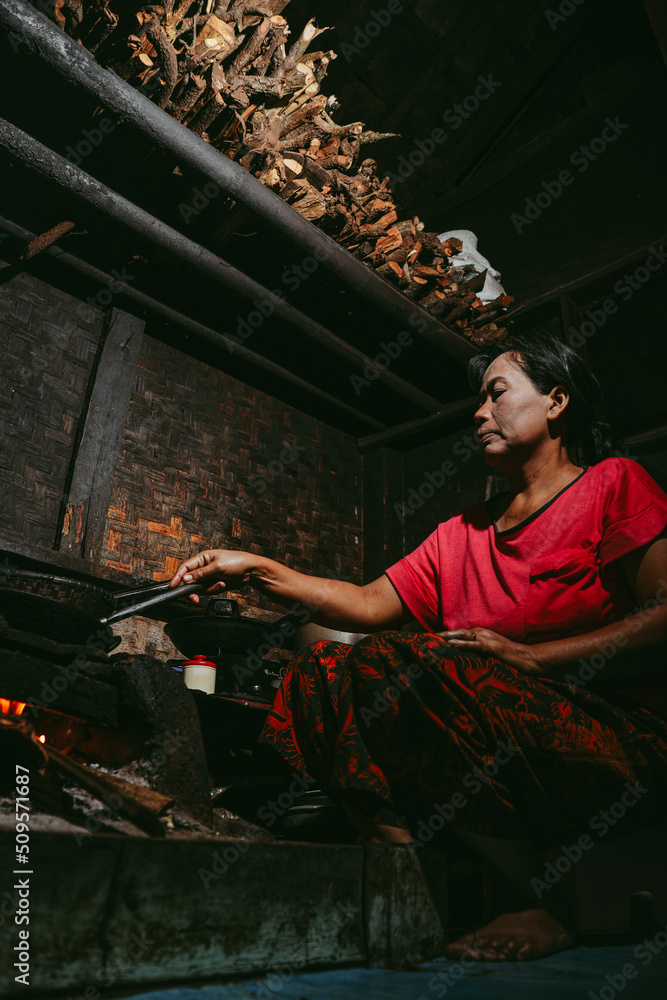 Asian local woman is cooking in traditional stove at wood cubicle ...