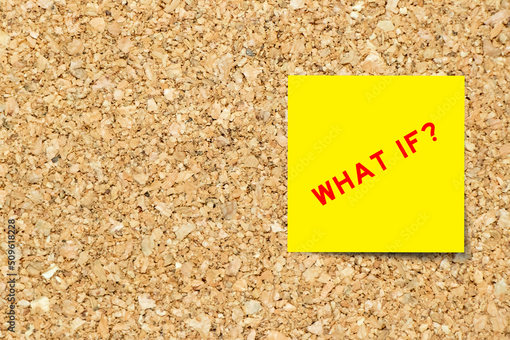 Yellow note paper with word what if on cork board background with copy ...