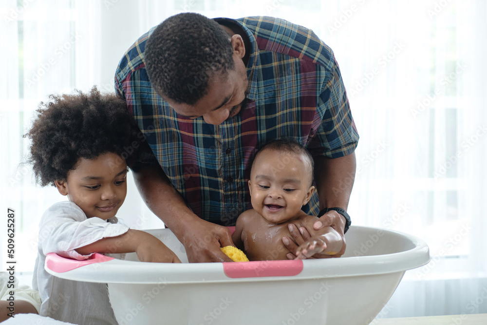 Happy African family, father bathing his baby daughter in bathtub ...