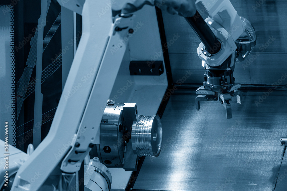 The automatic robotic arm gripping the metal parts from CNC lathe ...