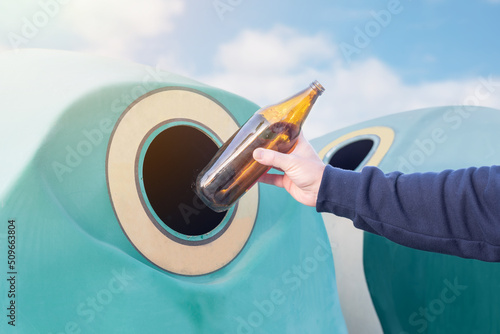 Man recycling glass. Throwing a glass bottle into a green recycling ...