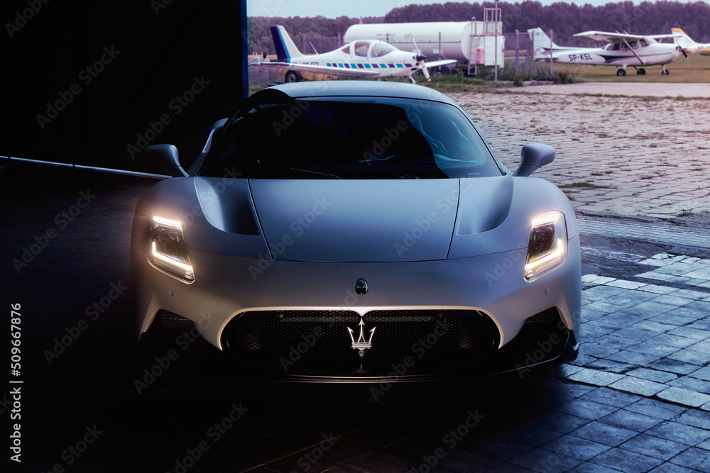 The front of the Maserati MC20 from a dark aircraft hangar. Small light ...