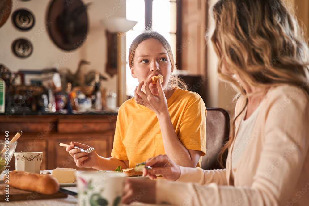 Caucasian teen girl eating and talking with her mother during the ...