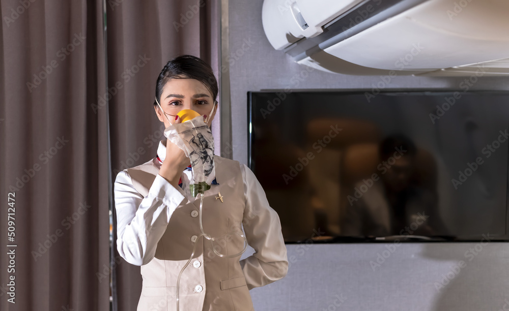 Asian female cabin crew demonstrate how to use oxygen mask on board ...