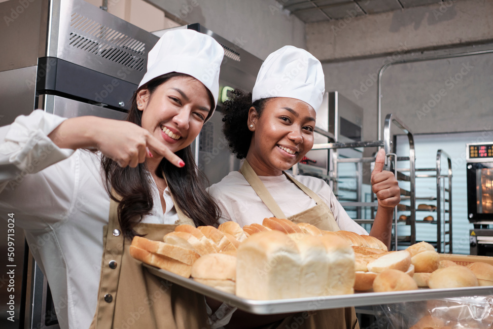 Portrait of two young female chefs in cooking uniform looking at camera ...
