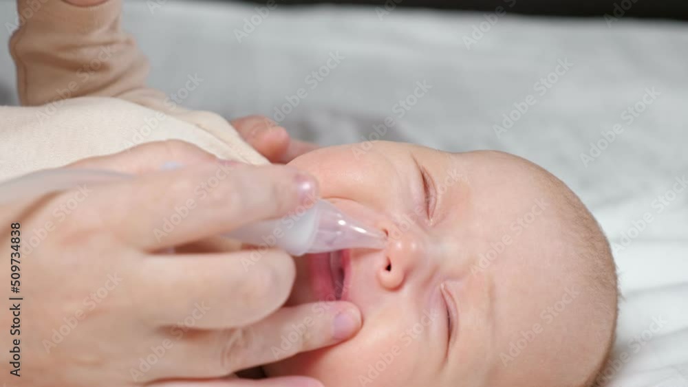Mother cleans nose of little girl from snot using aspirator on blurred ...