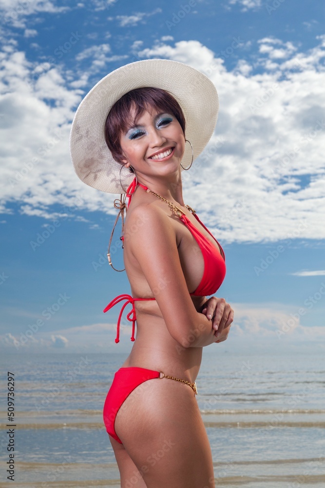 Sexy asian red bikini female lady model having a great holiday by a beach and posing happily ...
