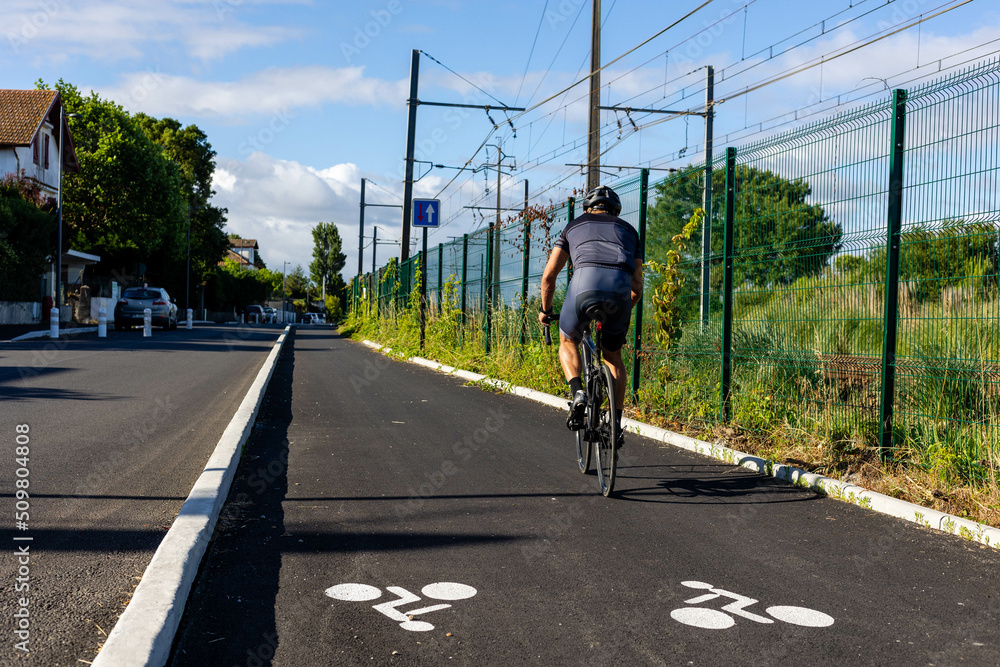 Piste cyclable avec un cycliste le long d'une route, la piste est ...