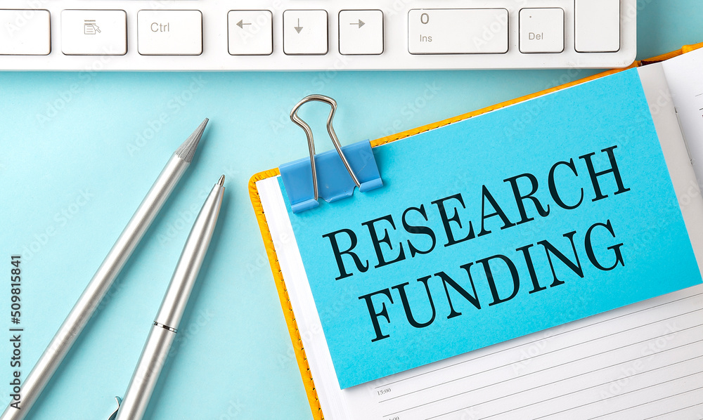 RESEARCH FUNDING text on sticker on the blue background with pen and ...