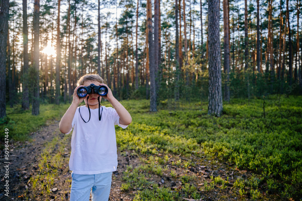 Preschooler boy is exploring nature with binoculars. Little child is ...