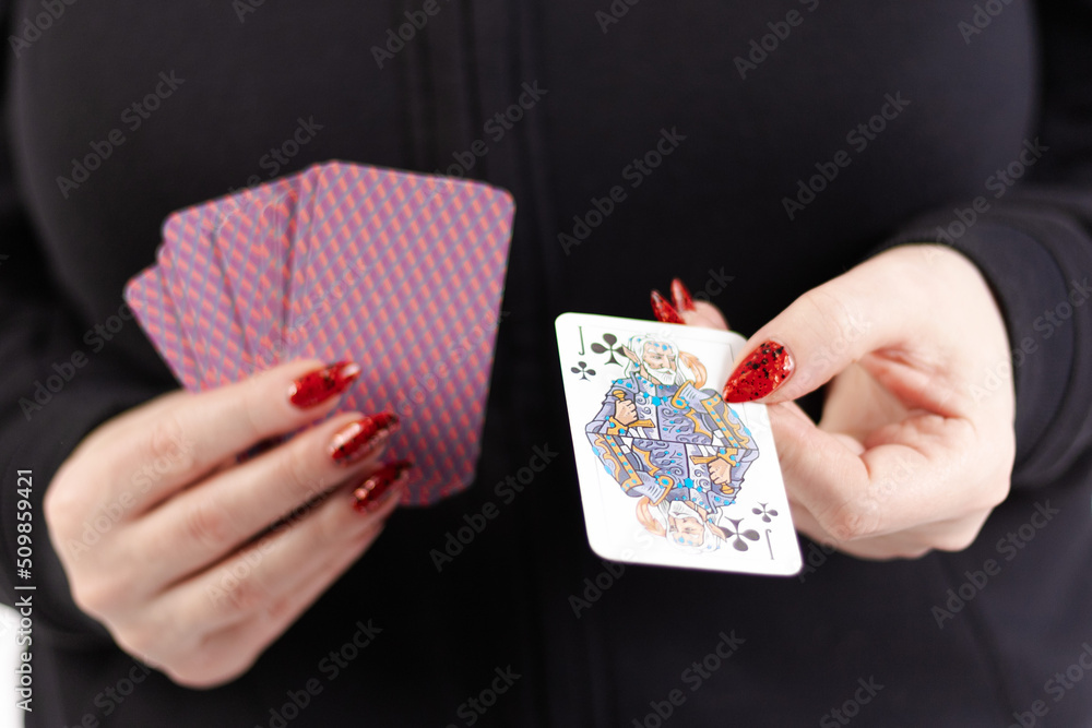 Female hands hold a deck of cards and show tricks. The photographer is ...