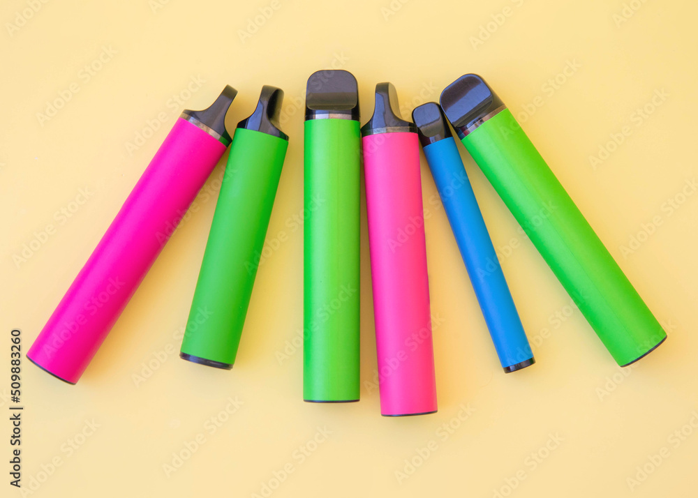 Six electronic vape cigarettes of different colors and sizes lie on a ...