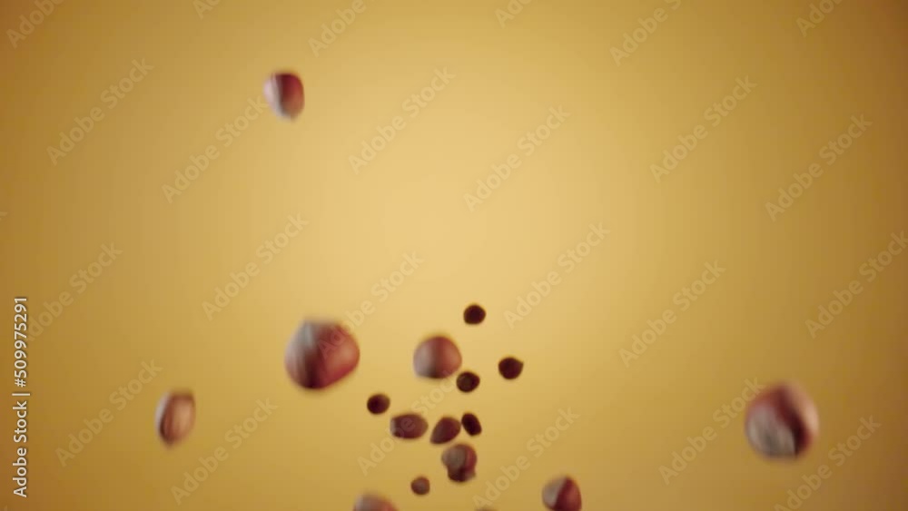 Explosion of dried kernel hazelnuts on yellow studio background. Brown ...