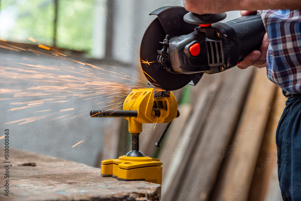 Workman grinding abrasive cutting by angle grinder. Man using vise ...