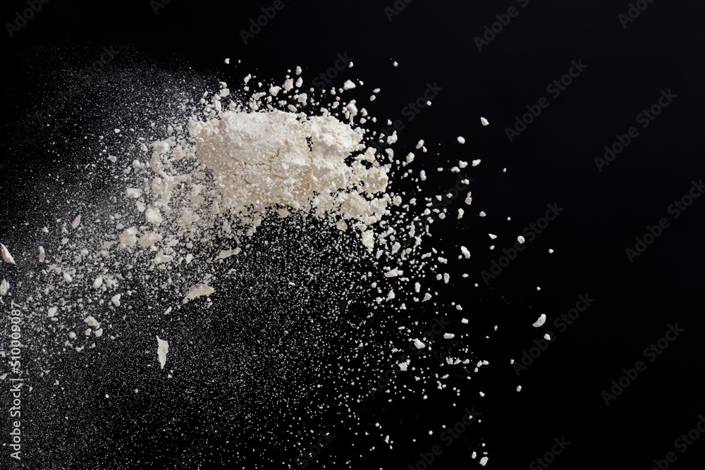 Flying white flour, powder on a black background. Spray of particles ...