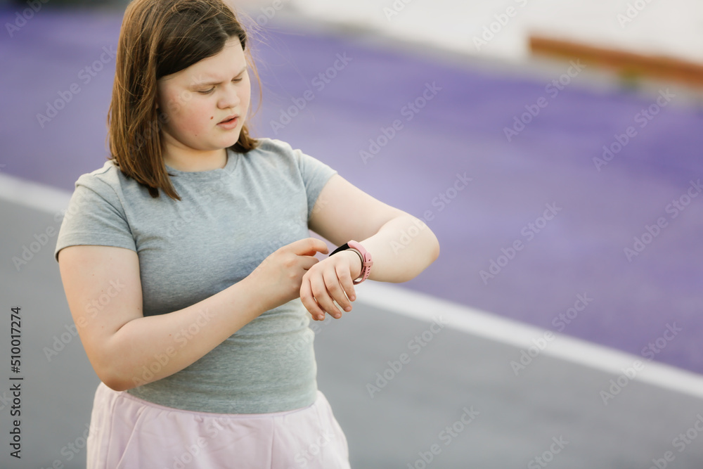Overweight European teenage girl in tracksuit watches time and distance ...
