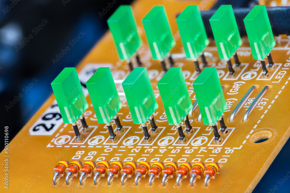 Green LED and orange semiconductor diodes at PCB detail on dark blur ...