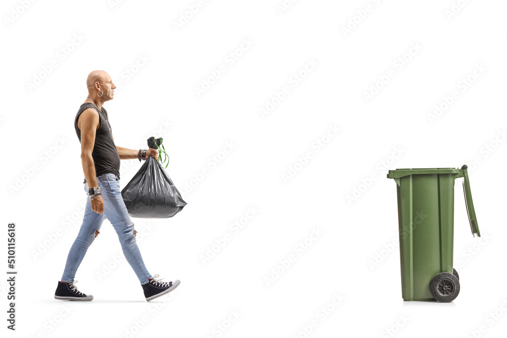 Bald man in ripped jeans carrying a plastic waste bag and walking ...