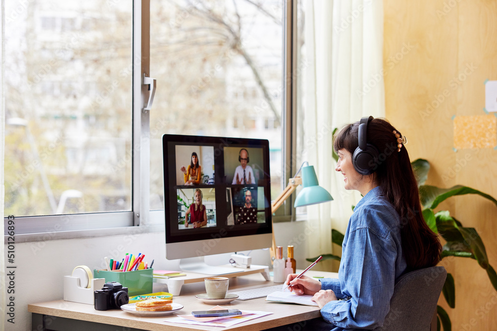 Female writing down data during online meeting Stock Photo | Adobe Stock