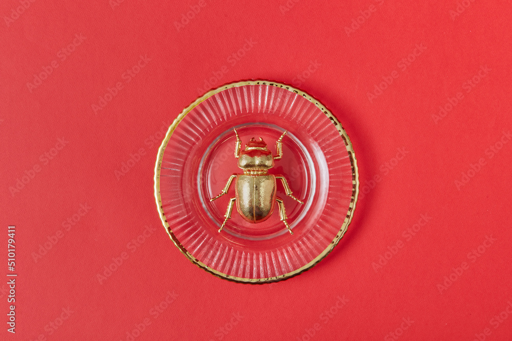Golden scarab beetle from metal on a glass plate. Stock Photo | Adobe Stock