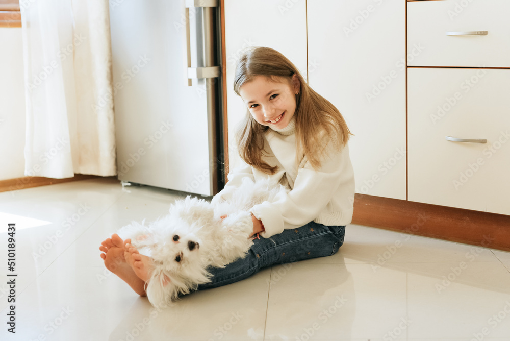 girl 9 years old with long hair model plays with pet white dog maltese ...
